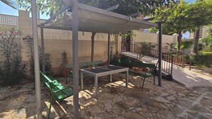 Uma área de pátio com pérgola, mesa e bancos.
