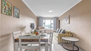 Uma área de refeições com uma mesa posta para dois, um sofá e uma pequena mesa redonda.