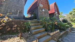 Um edifício com telhado inclinado e escadaria que dá acesso à entrada.