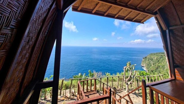 Estrutura de madeira com vista para o oceano e paisagem montanhosa.