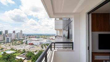 Uma varanda com vista para a cidade, uma televisão na parede e uma porta que dá para o interior.