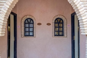 Fachada de edifício com duas janelas em arco, cada uma com uma pequena placa acima.