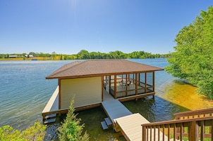 Uma casa ancorada com um alpendre coberto, um pequeno deck e vista para um lago.