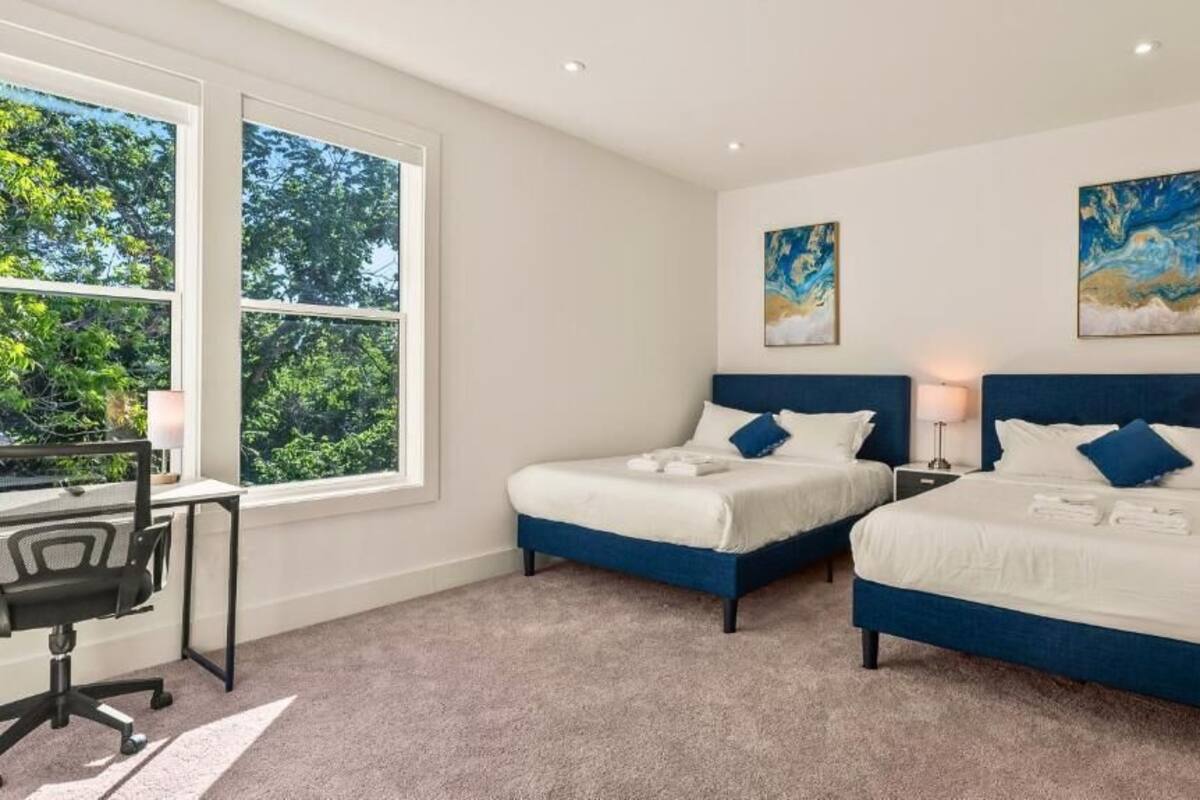 Quarto com duas camas, uma escrivaninha e janelas amplas.