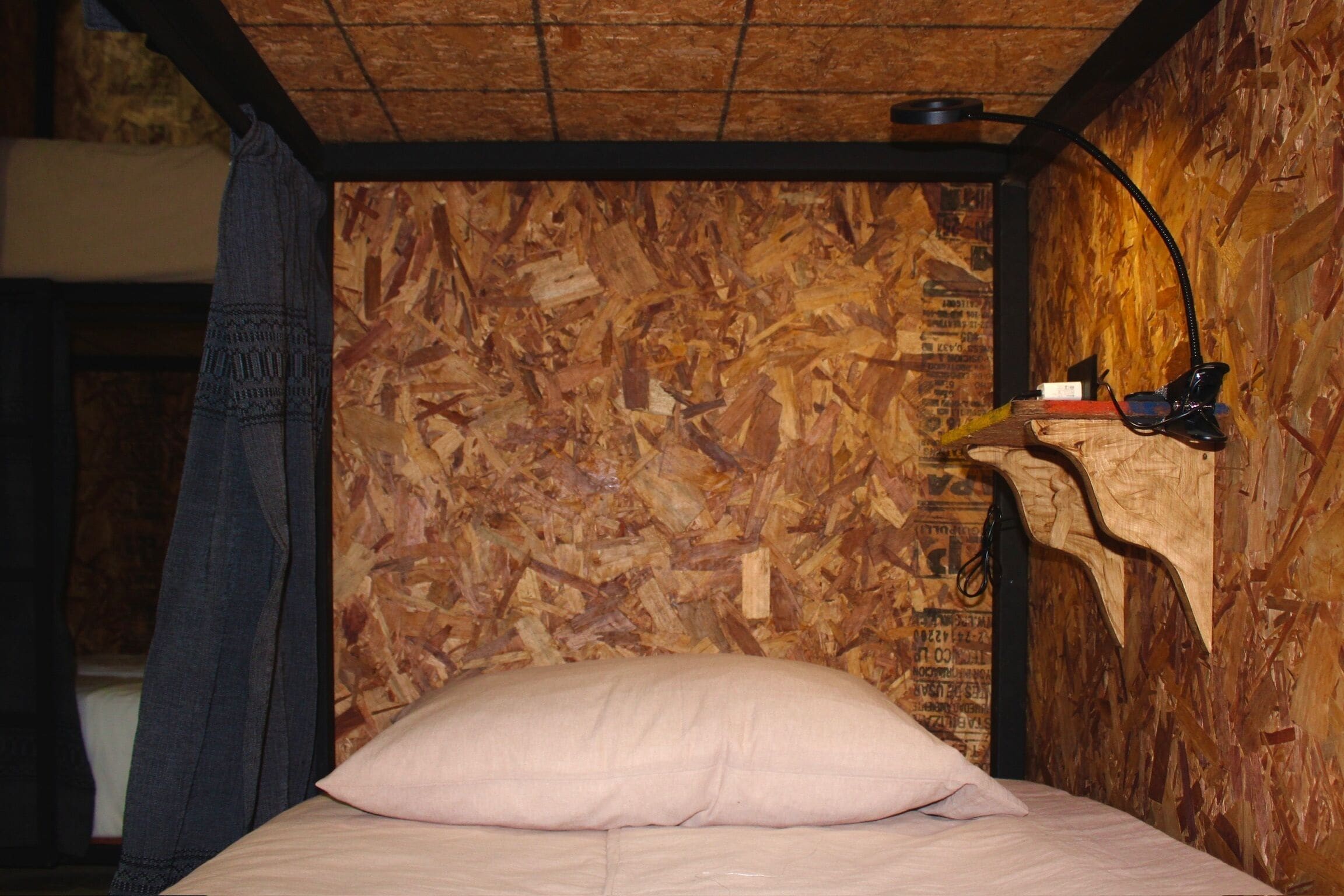 Uma cama com travesseiro em quarto com paredes de madeira e teto inclinado.