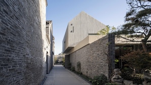 Um beco estreito ladeado por edifícios de tijolo, com uma estrutura moderna e telhado inclinado.
