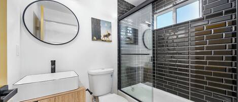 Uma casa de banho moderna com uma pia, sanita e banheira brancas.