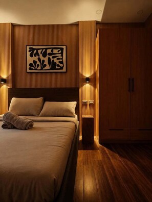 Quarto com cama, painéis de madeira, uma obra de arte na parede e um guarda-roupa.