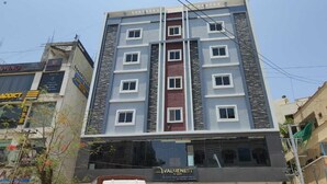 Hotel com vários andares e fachada moderna, com elemento de design vertical central e diversas janelas por andar.