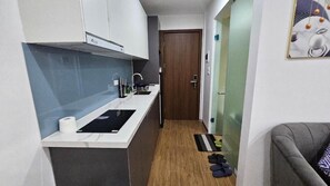 Uma cozinha compacta com bancada, pia e uma porta que dá para outro espaço.