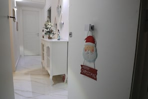 Um corredor com uma porta branca, uma pequena árvore de Natal e uma decoração de Papai Noel.