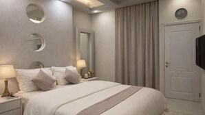 Quarto com cama, mesas de cabeceira, espelho, relógio e porta.