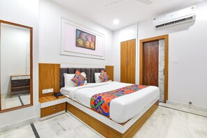 Quarto com cama, mesas de cabeceira, guarda-roupa, espelho e ar condicionado.