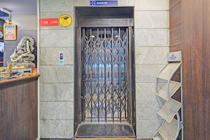 Um elevador com uma câmera de segurança, um aviso de vigilância e uma placa indicando a área do elevador.