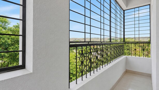 Varanda com guarda-corpo de metal e vista para o verde.
