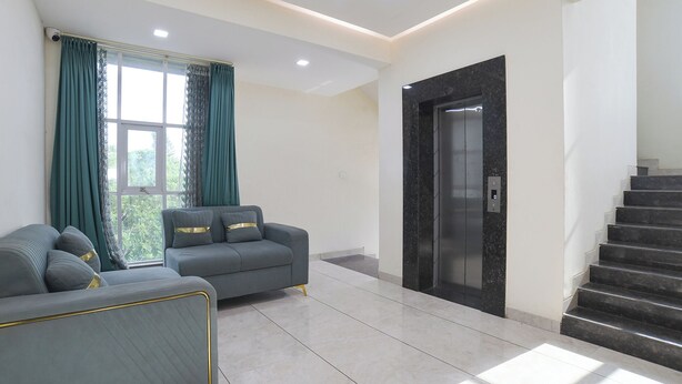 Uma sala de estar moderna com um sofá, uma escada e uma porta que dá para um elevador.