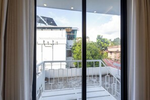 Uma varanda com guarda-corpo branco, vista para edifícios e céu claro.