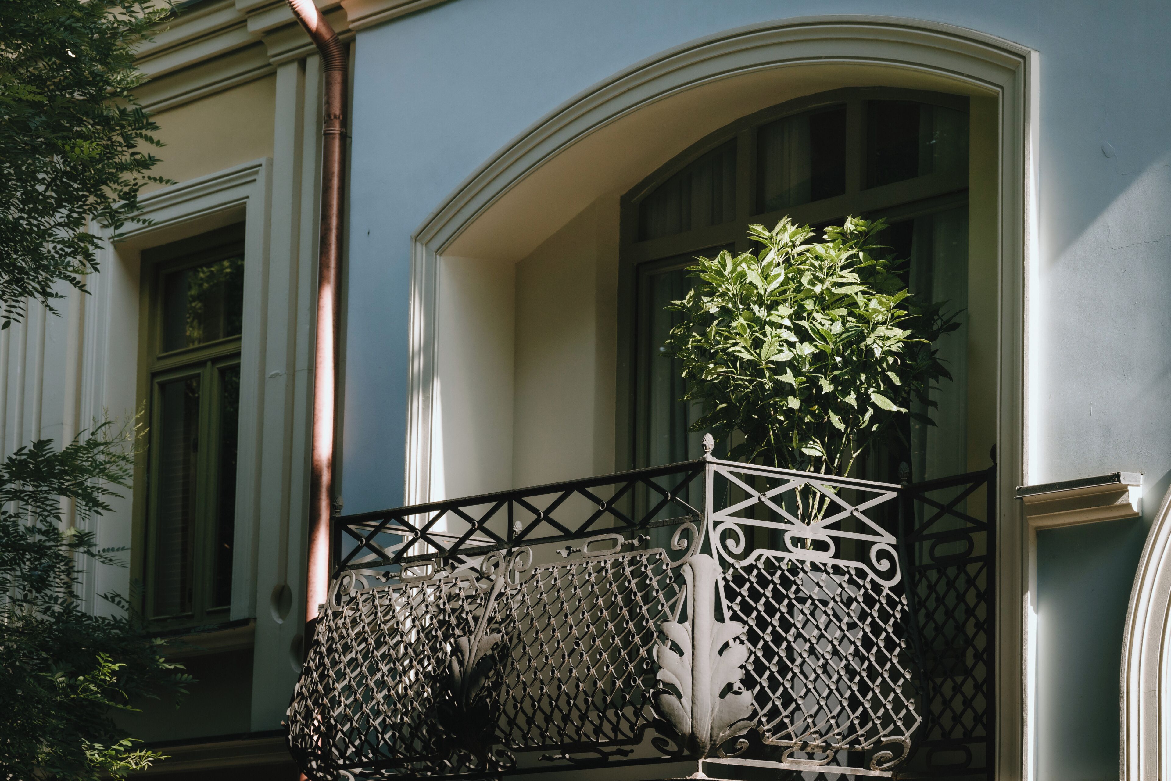 Um edifício com varanda, com grade de ferro forjado e um vaso de planta.