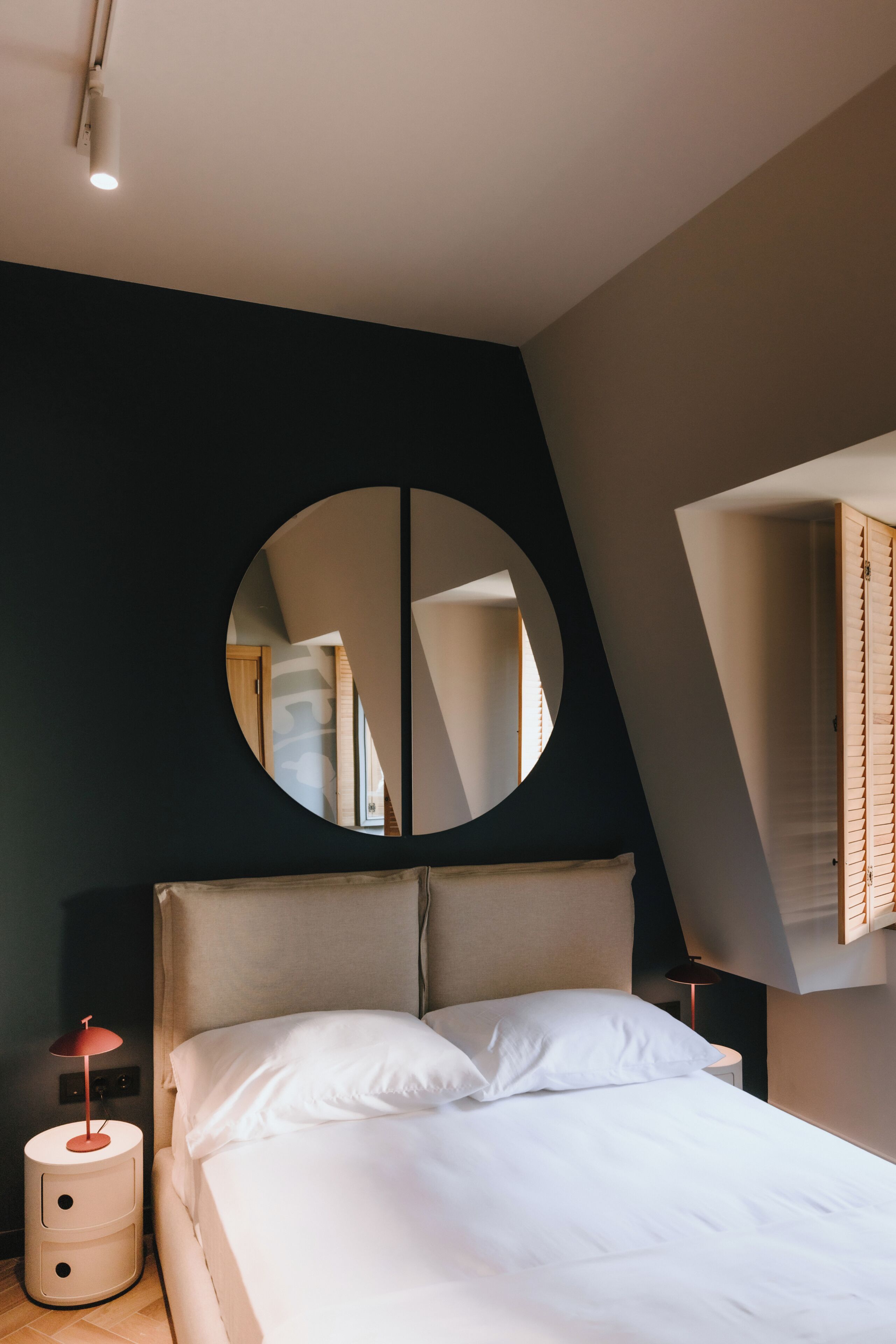 Quarto com cama, espelho redondo, mesa de cabeceira e armário.