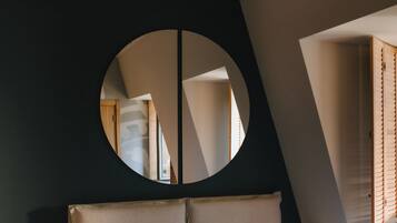 Quarto com cama, espelho redondo, mesa de cabeceira e armário.