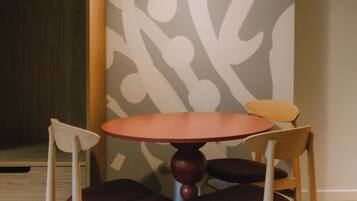 Uma sala de jantar com uma mesa redonda e duas cadeiras, um lustre e um papel de parede estampado.