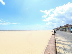 Uma praia com uma passarela, uma torre de salva-vidas e uma fileira de edifícios coloridos.