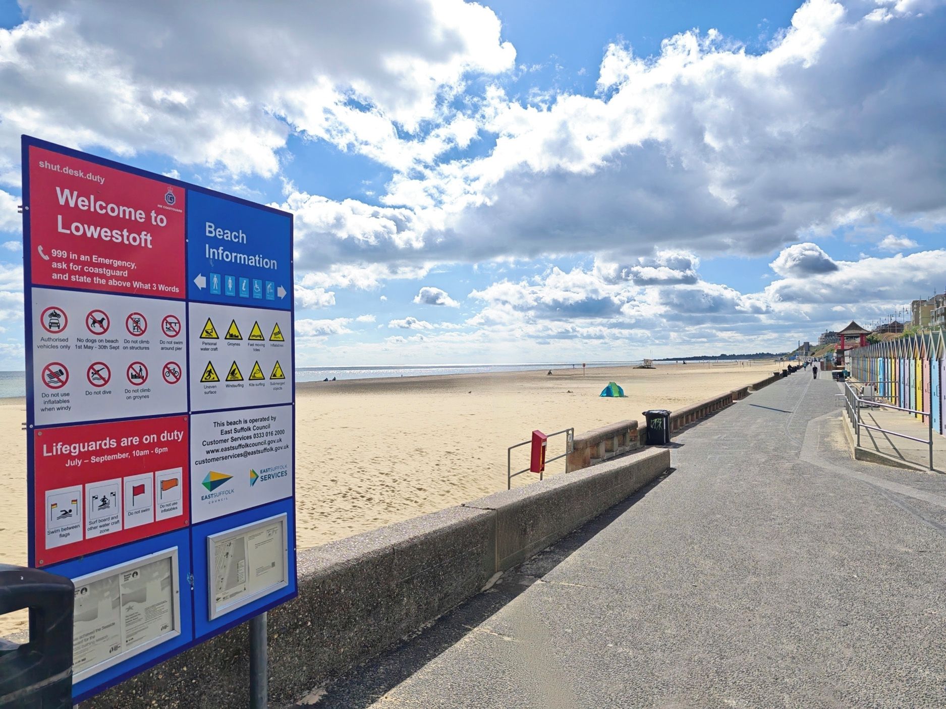 Placa de informações da praia com orientações de segurança e horários dos salva-vidas.