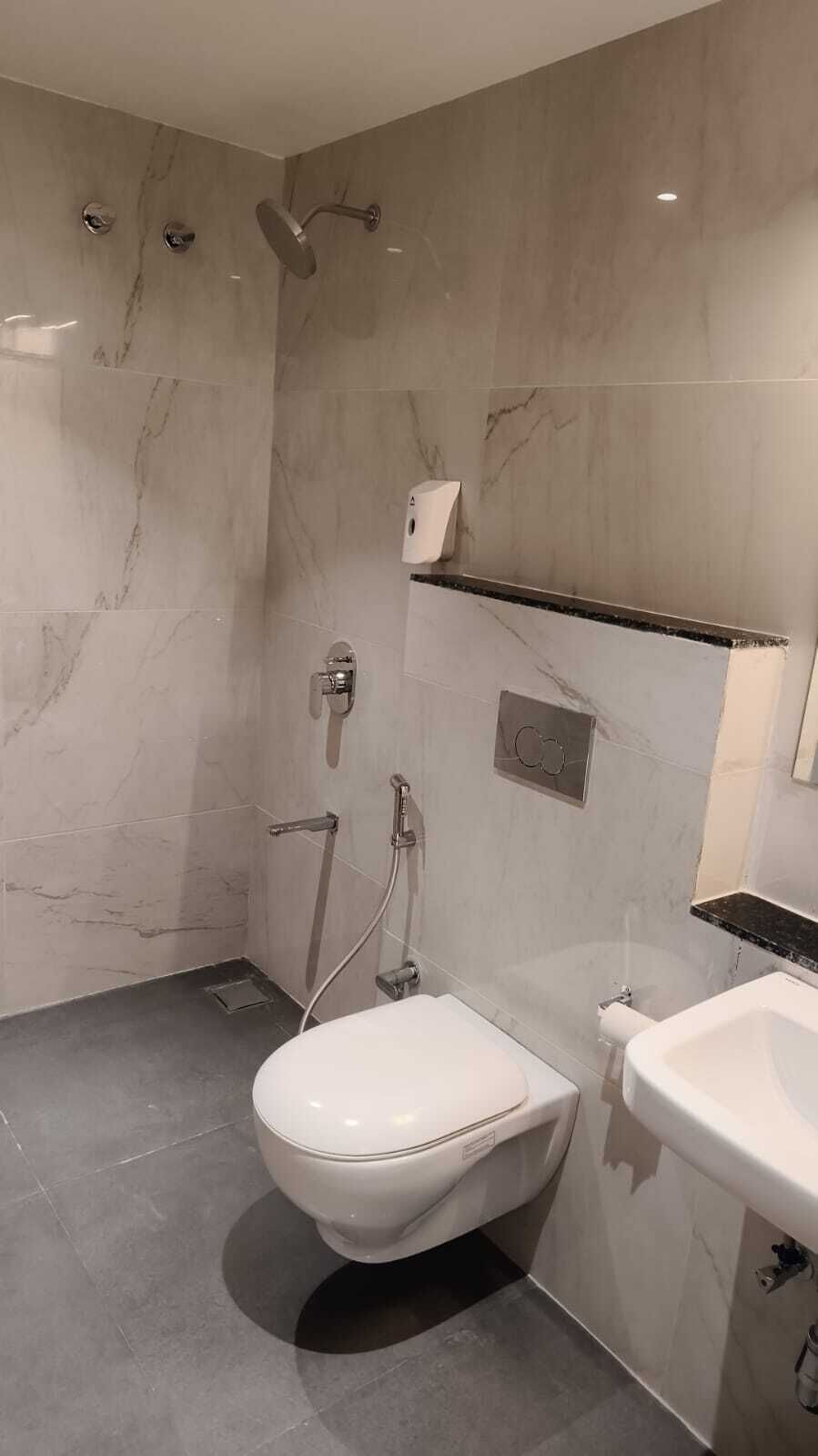Uma casa de banho moderna com sanita, bidé e chuveiro.
