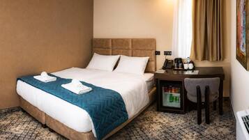 Quarto de hotel com cama, escrivaninha, cadeira, máquina de café e minibar.
