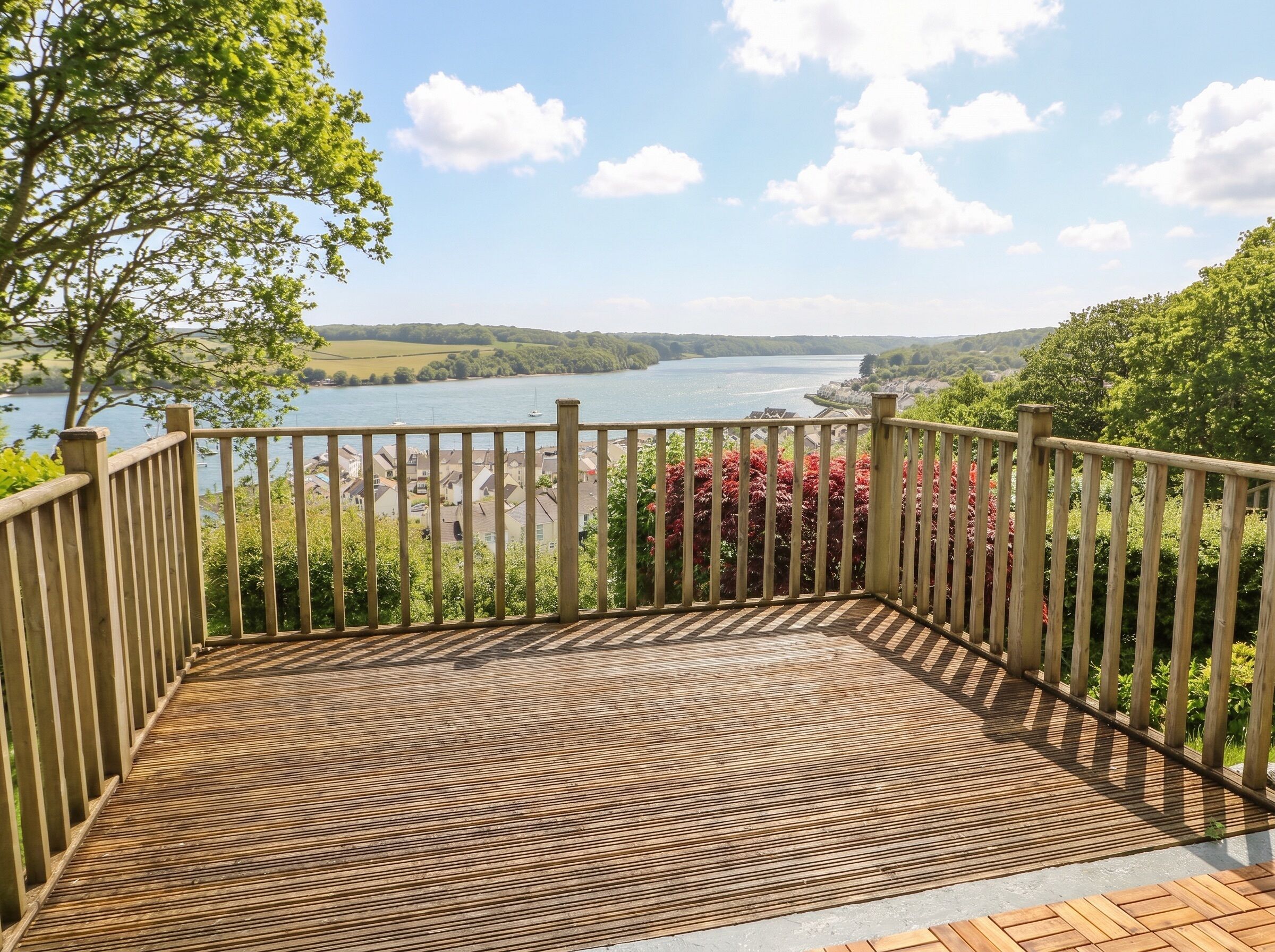 Um deck de madeira com vista para um lago e vegetação ao redor.