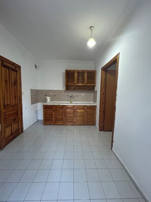 Uma cozinha com armários de madeira, painel de azulejos e uma luminária no teto.