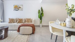 Uma sala moderna com sofá, pufê, mesa de centro e um espaço de jantar com cadeiras e mesa.