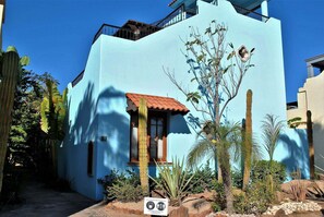 Um edifício com fachada azul, uma pequena janela e uma placa que indica exigência de altura de 1,88 metros.