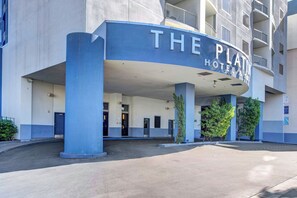 O Plaza Hotel, com fachada azul e branca, várias portas e área de entrada coberta.