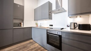 Uma cozinha moderna com armários cinzas, forno embutido e exaustor de aço inoxidável.