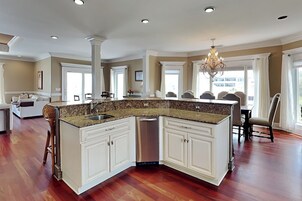 Uma cozinha espaçosa com ilha central, armários brancos e um lustre.