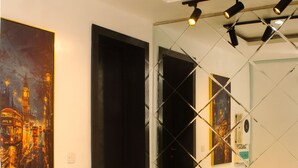 Quarto com uma pintura grande, divisória de vidro e luminária no teto.