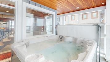 Uma banheira de hidromassagem em um quarto com teto de madeira e grandes janelas.