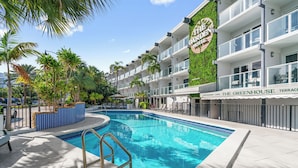 Um hotel com piscina, um restaurante chamado 'The Greenhouse Terrace' e uma placa com a inscrição 'The Garden Hotel'.
