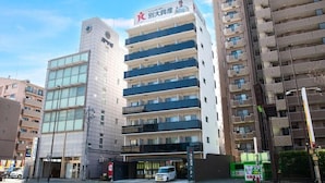 Um edifício de vários andares com uma placa chamativa, uma área de estacionamento e uma carrinha branca estacionada em frente.
