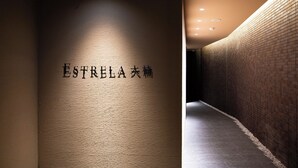 Um corredor com parede texturizada e piso ladrilhado, que leva a um quarto com parede de tijolos e iluminação embutida.