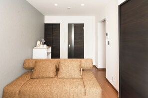 Quarto moderno com sofá, uma mesinha de cabeceira com abajur e um guarda-roupa.