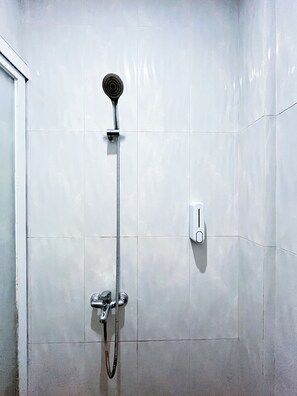 Chuveiro com chuveiro manual, painel de controle fixado na parede e saída de água visível.