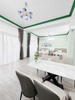 Uma área de jantar moderna com uma mesa branca, cadeiras cinzentas e um candelabro.