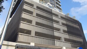 Um edifício alto com um letreiro que diz 'THE STRAITS' e 'PANGSAPURI SELAT', indicando um hotel ou resort.