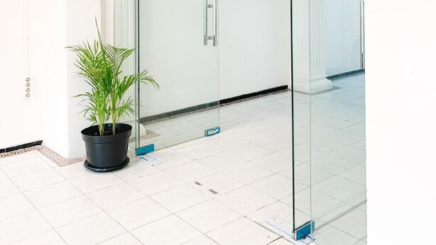 Um interior moderno com divisória de vidro, um vaso de planta e piso revestido de azulejos.