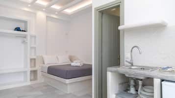 Quarto moderno com cama, estantes embutidas, banheiro com pia e espelho, e closet espaçoso.