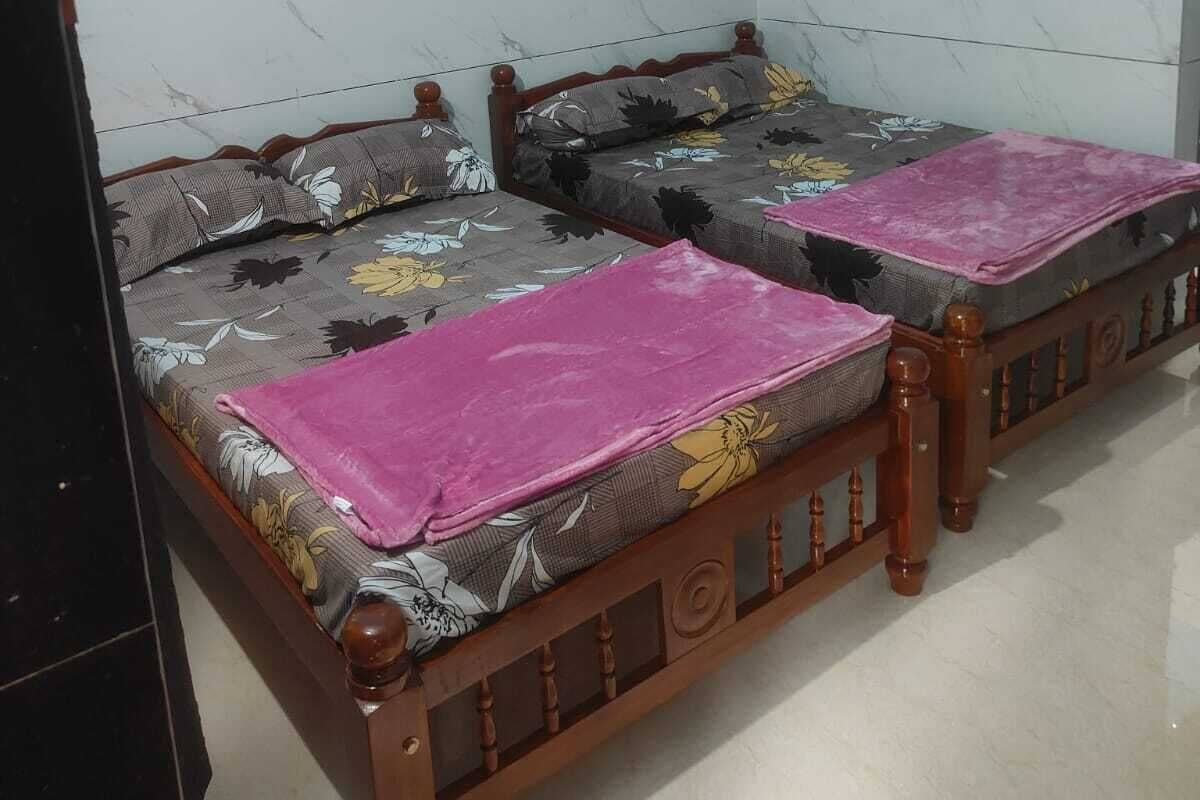 Quarto com duas camas de madeira, um ventilador de teto e ar condicionado.
