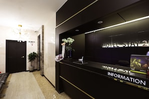 Balcão de recepção de hotel com uma placa que diz 'HOTEL STAY 24 INFORMAÇÕES'.