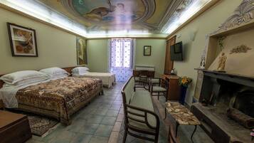 Quarto com cama, duas cadeiras, escrivaninha, lareira e um mural no teto.
